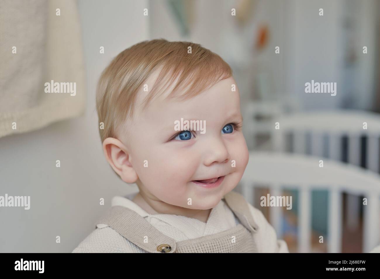 Wonderful baby boy with blue eyes. Child playing with toys in nursery ...