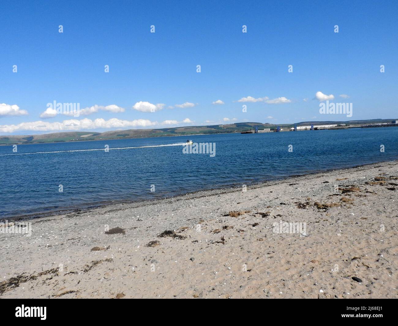 Loch Ryan, Scotland, a jet skier with Stranraer pier and railway ...