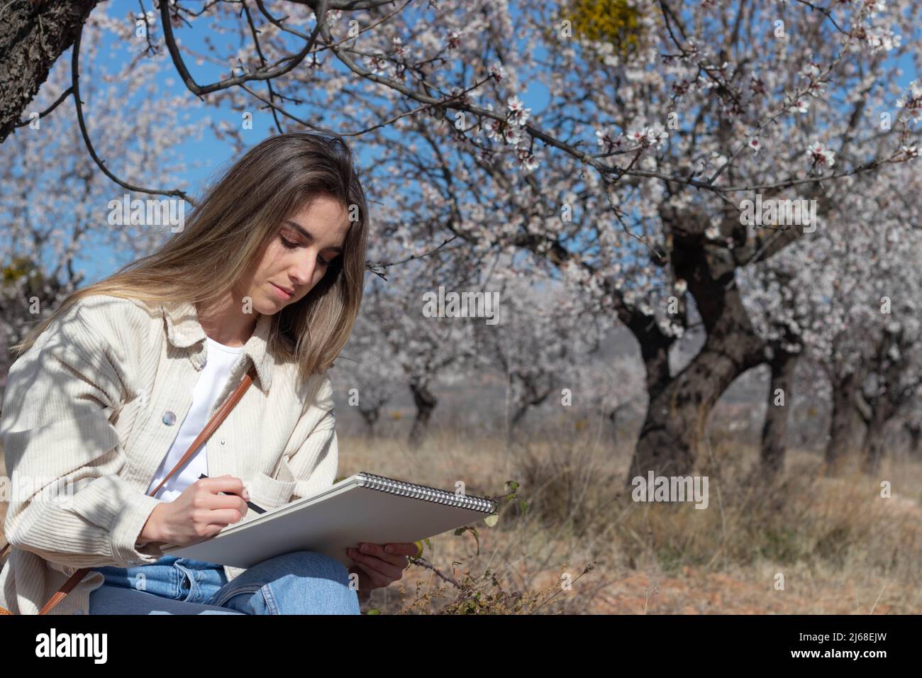 Portrait of a young and beautiful woman focused on her nature landscape ...