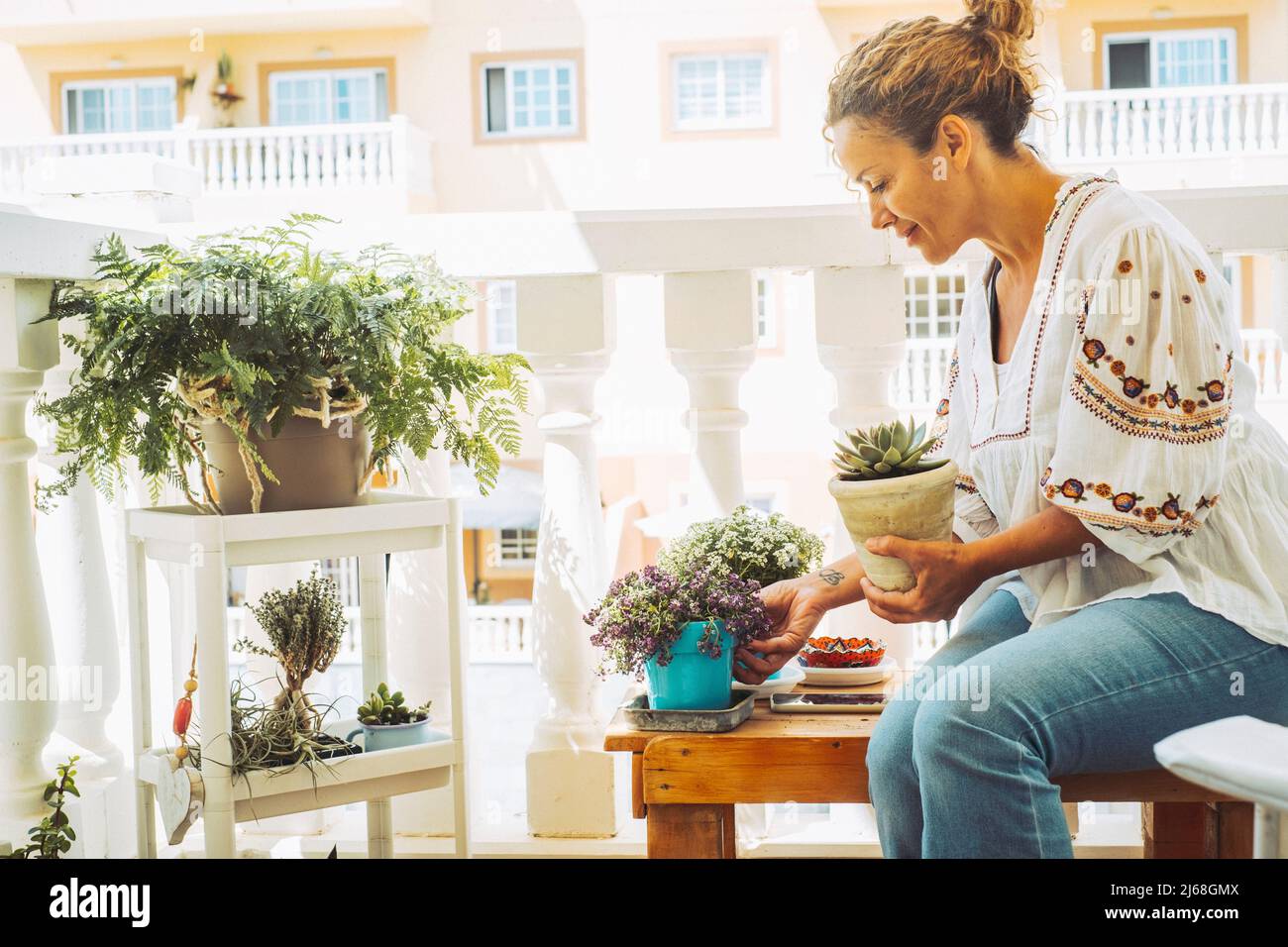 Adult woman in gardening activity outside home in the terrace. Female ...