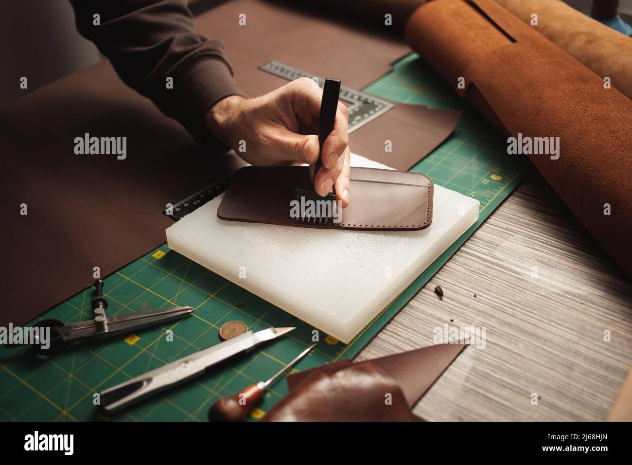 leatherworker punches holes. Tanner works with leather, small business ...