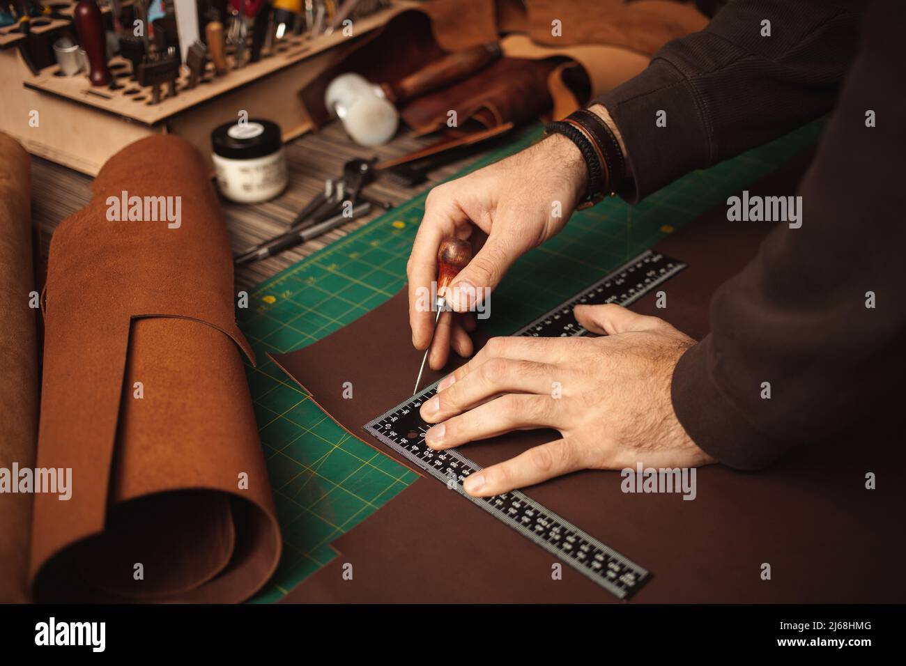 leatherworker draws, measures with ruler. Tanner works with leather ...