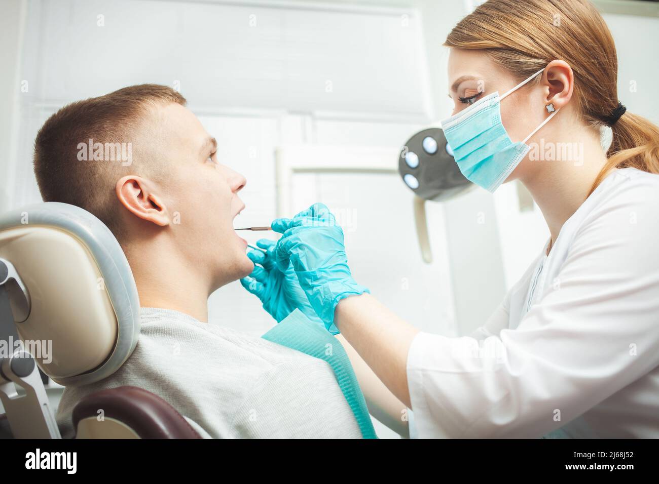 European female dentist doctor treats patient, examines mouth and teeth ...