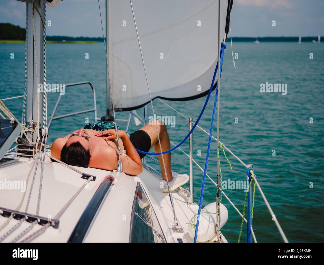 young person sunbathing on a sailboat under the sail Stock Photo - Alamy
