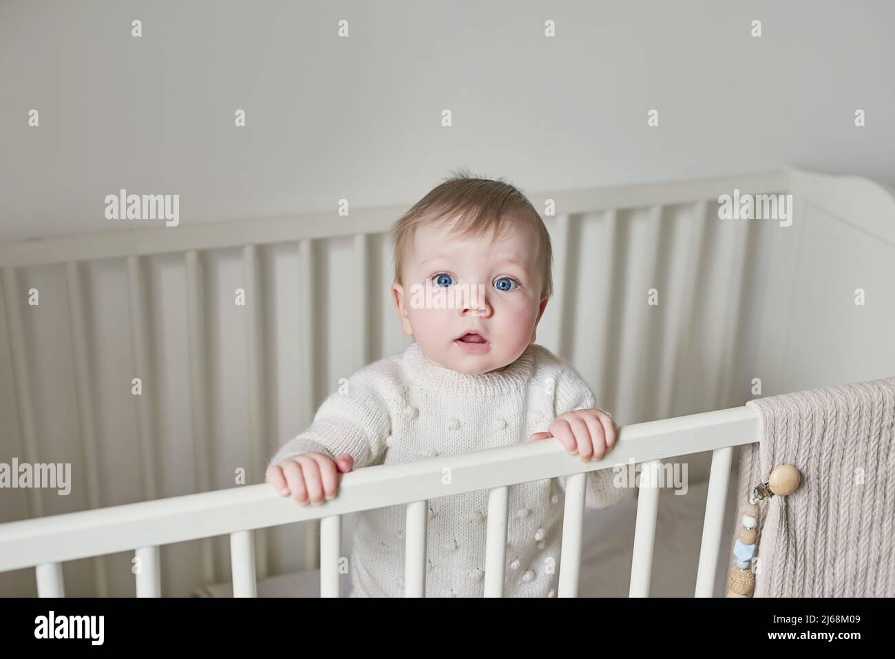 Wonderful baby boy with blue eyes in crib. Child playing with toys in ...