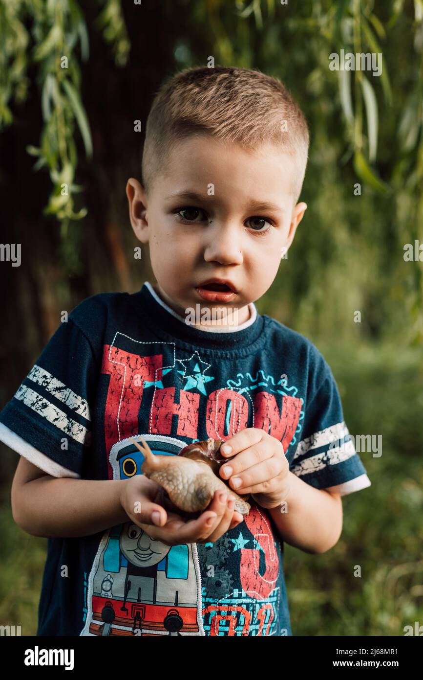 A small child holds toys in his hands and surprised in nature under a ...