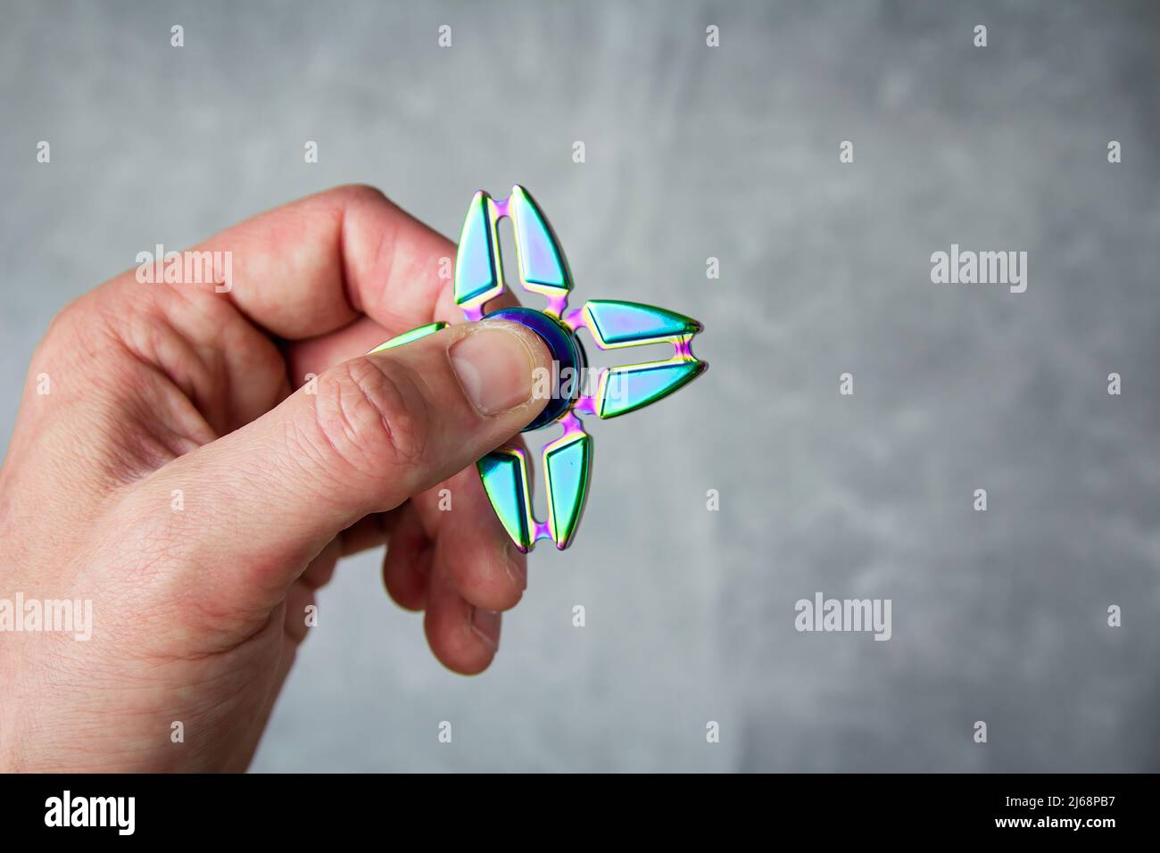 Man hand holding colorful metalic fidget spinner on marble background ...