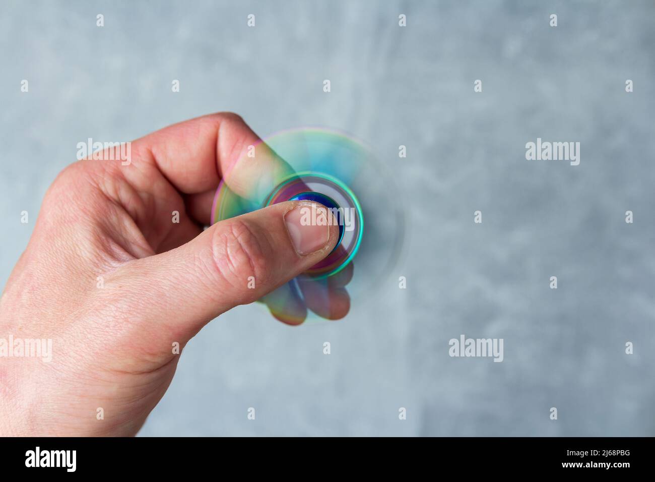 Man hand holding rotating metalic fidget spinner on marble background ...