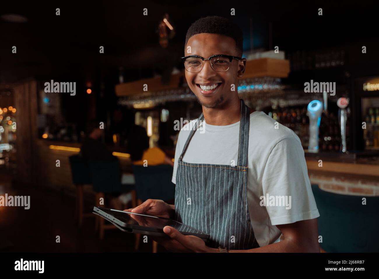 African American male waiter smiling holding digital tablet Stock Photo ...