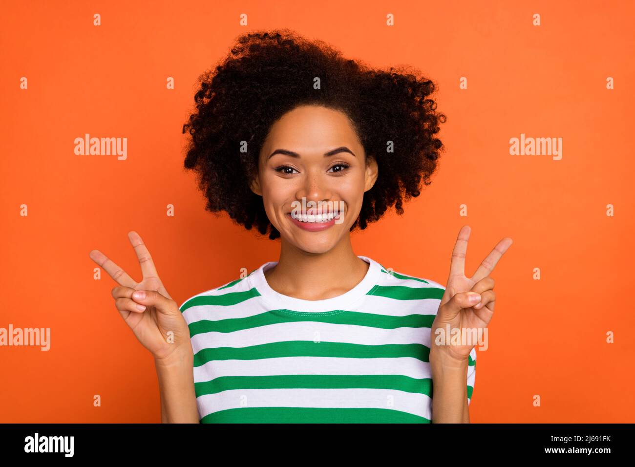 Portrait of attractive cheerful wavy-haired girl showing double v-sign ...