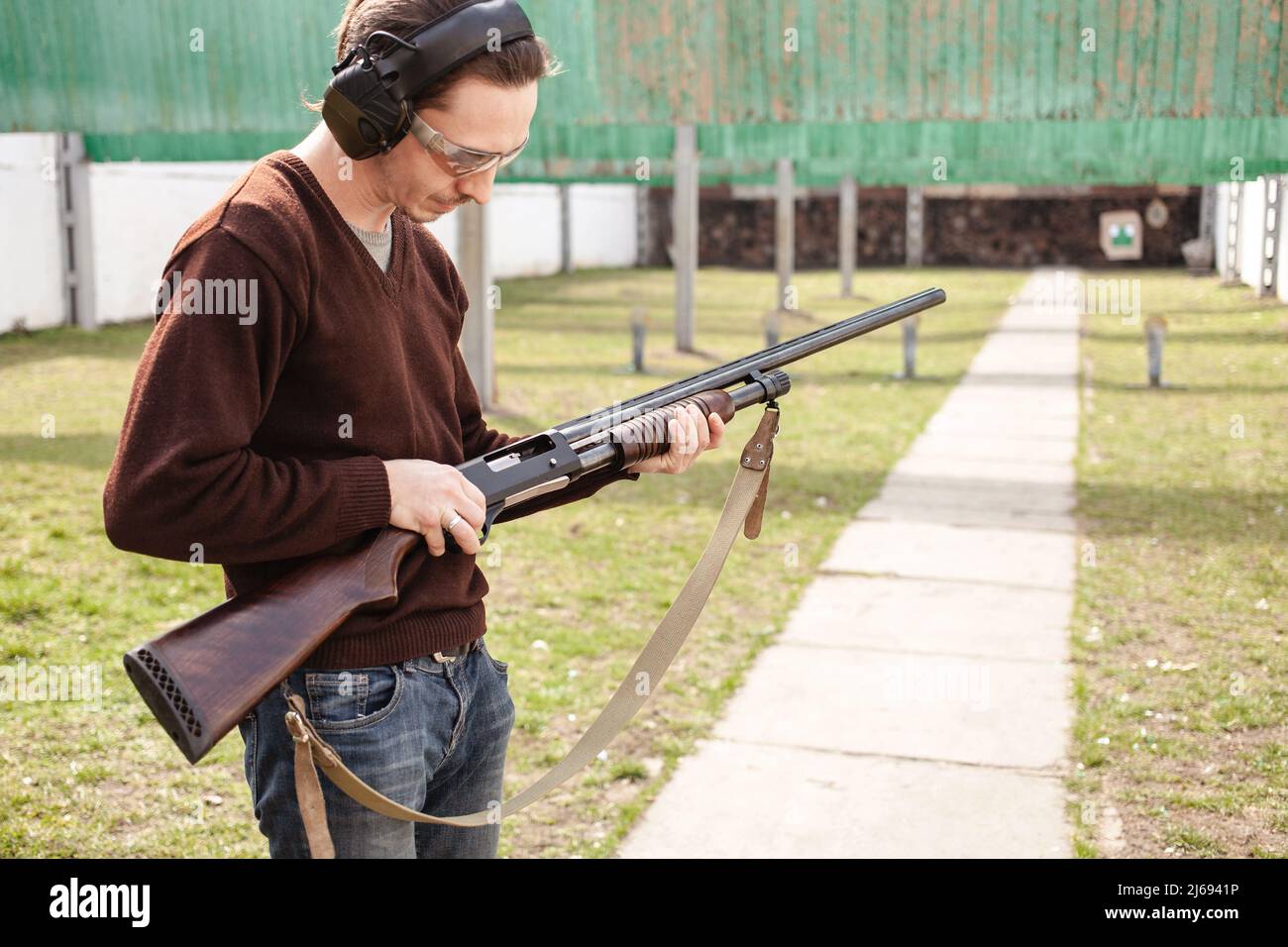 A young man charges a pump-action shotgun with a Ammo. 12 caliber. Tyre ...