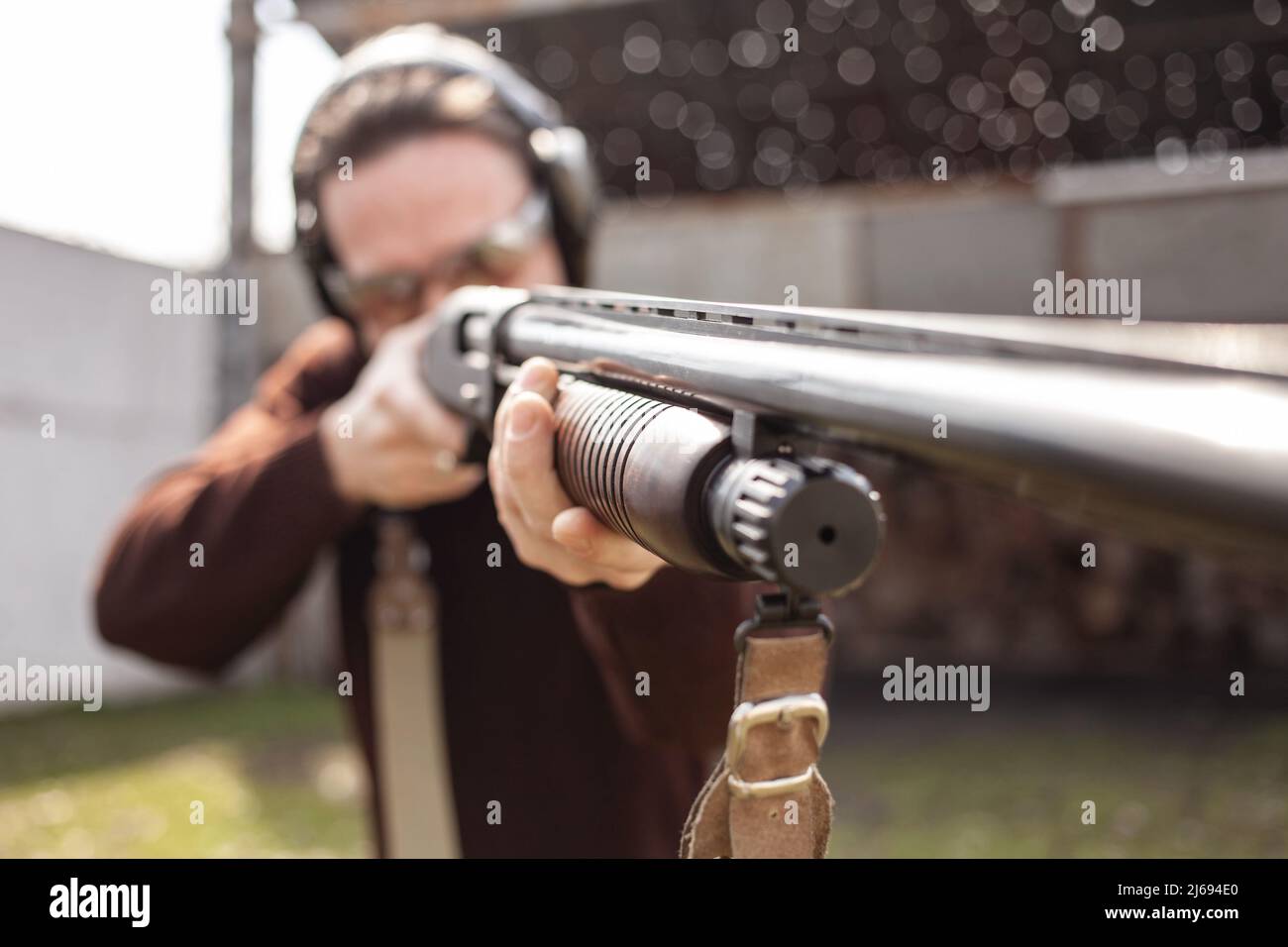 A young man in protective glasses and headphones. A pump-action shotgun ...