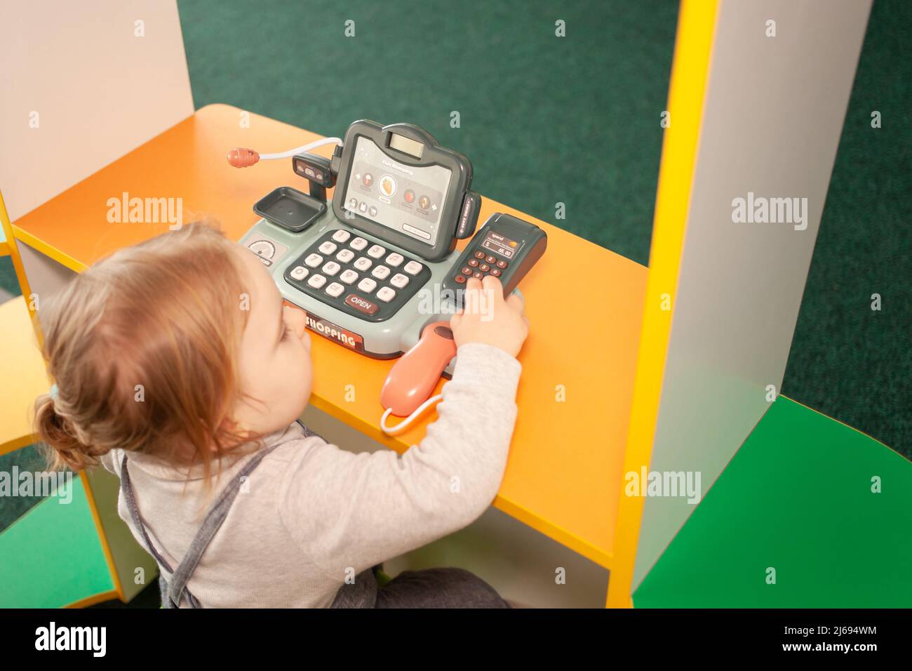 A small two-year-old girl plays with toys in the playroom. Development ...