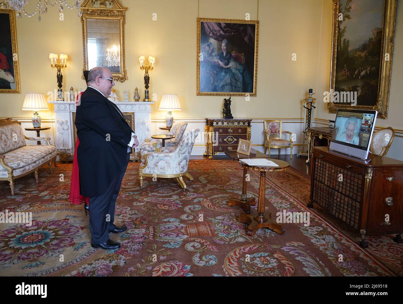 Queen Elizabeth II, in residence at Windsor Castle, appears on a screen ...
