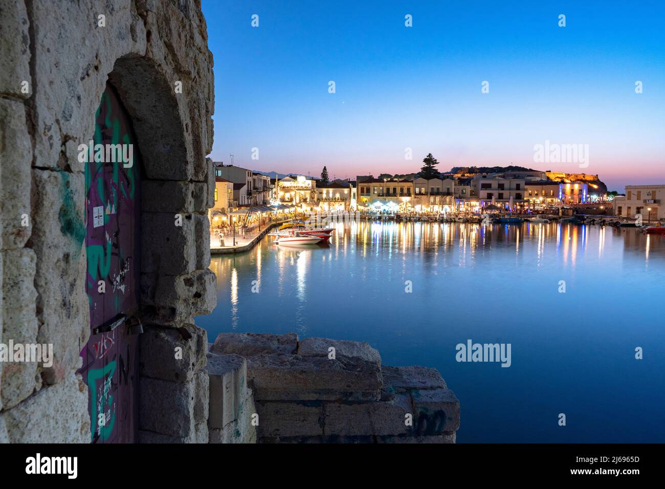 Lights of old Venetian port reflected in the sea at dusk, Rethymno ...