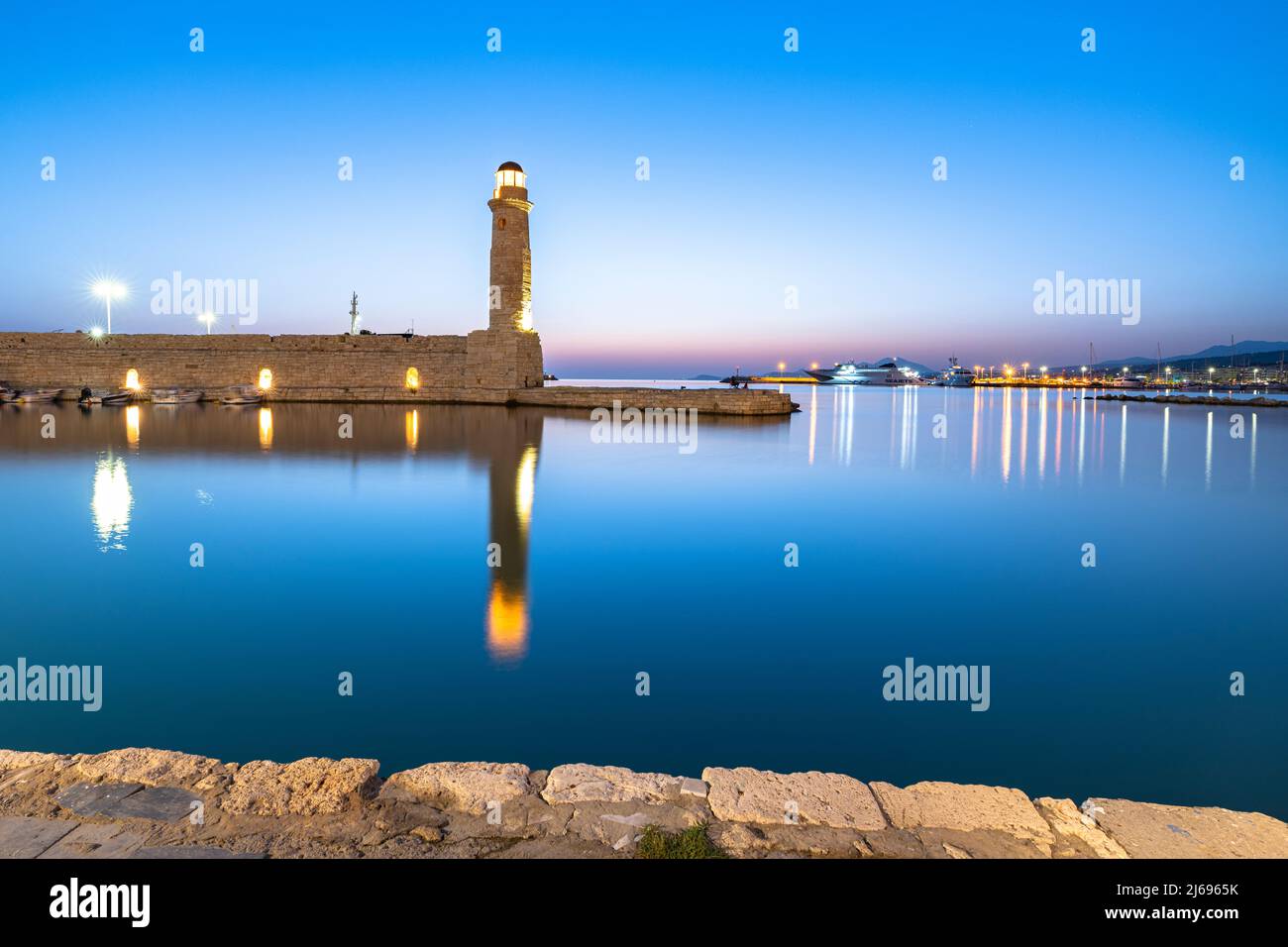 Old lighthouse reflected in the calm sea during the blue hour, Rethymno ...