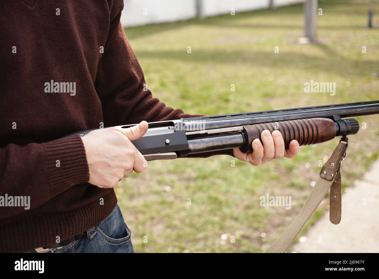 A young man charges a pump-action shotgun with a Ammo. 12 caliber. Tyre ...