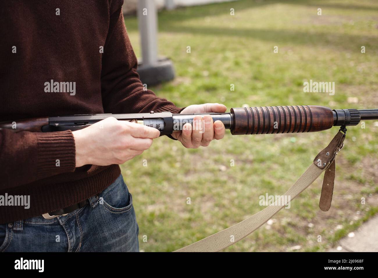 A young man charges a pump-action shotgun with a Ammo. 12 caliber. Tyre ...