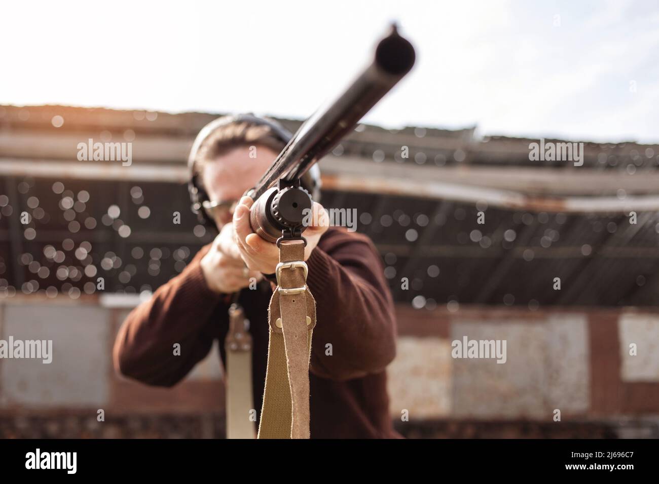 A young man in protective glasses and headphones. A pump-action shotgun ...