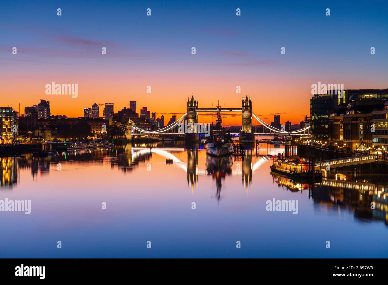 Tower Bridge, HMS Belfast and reflections in a still River Thames at sunrise, London, England ...