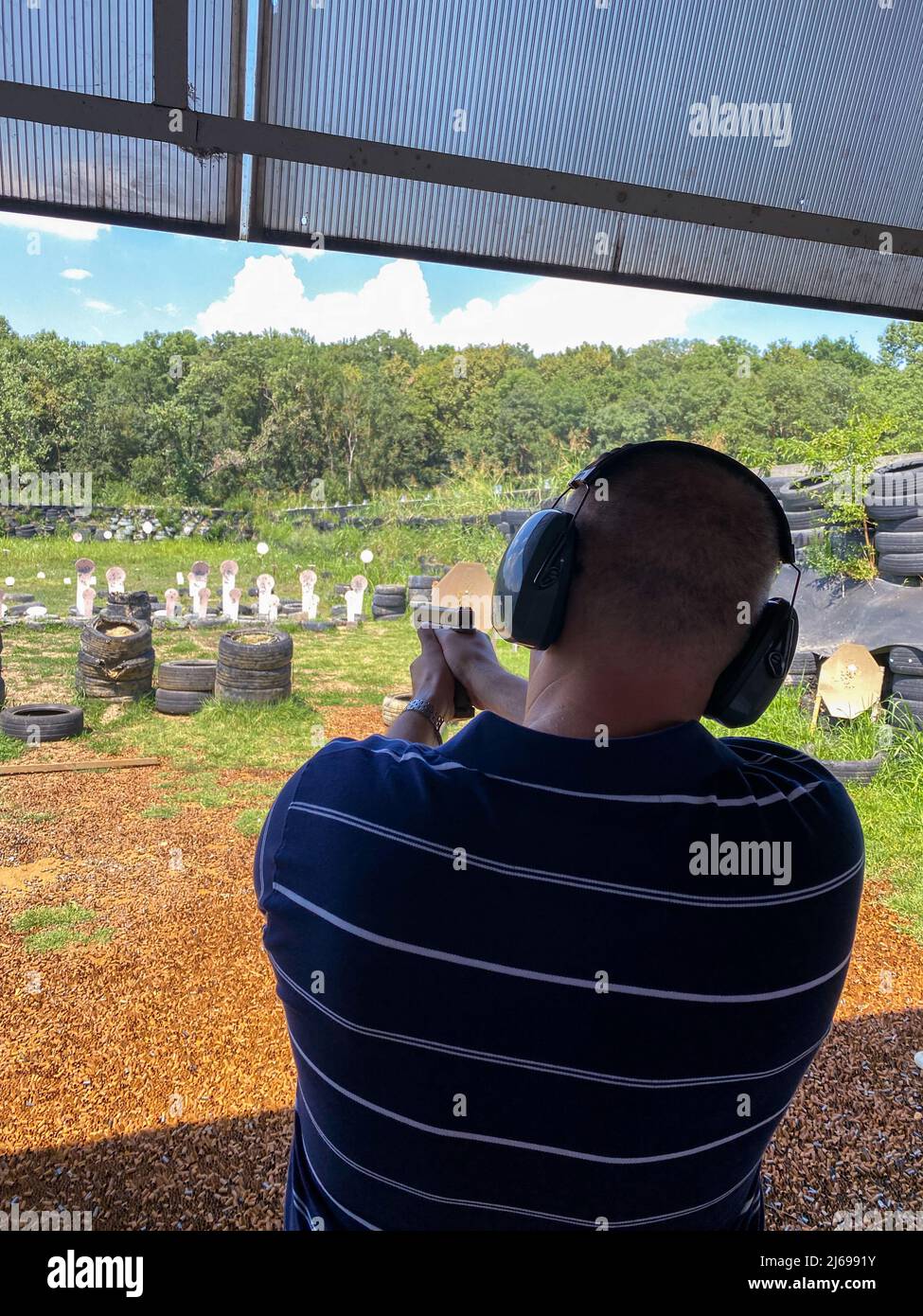 Man firing pistol at target in outdoor shooting range Stock Photo - Alamy