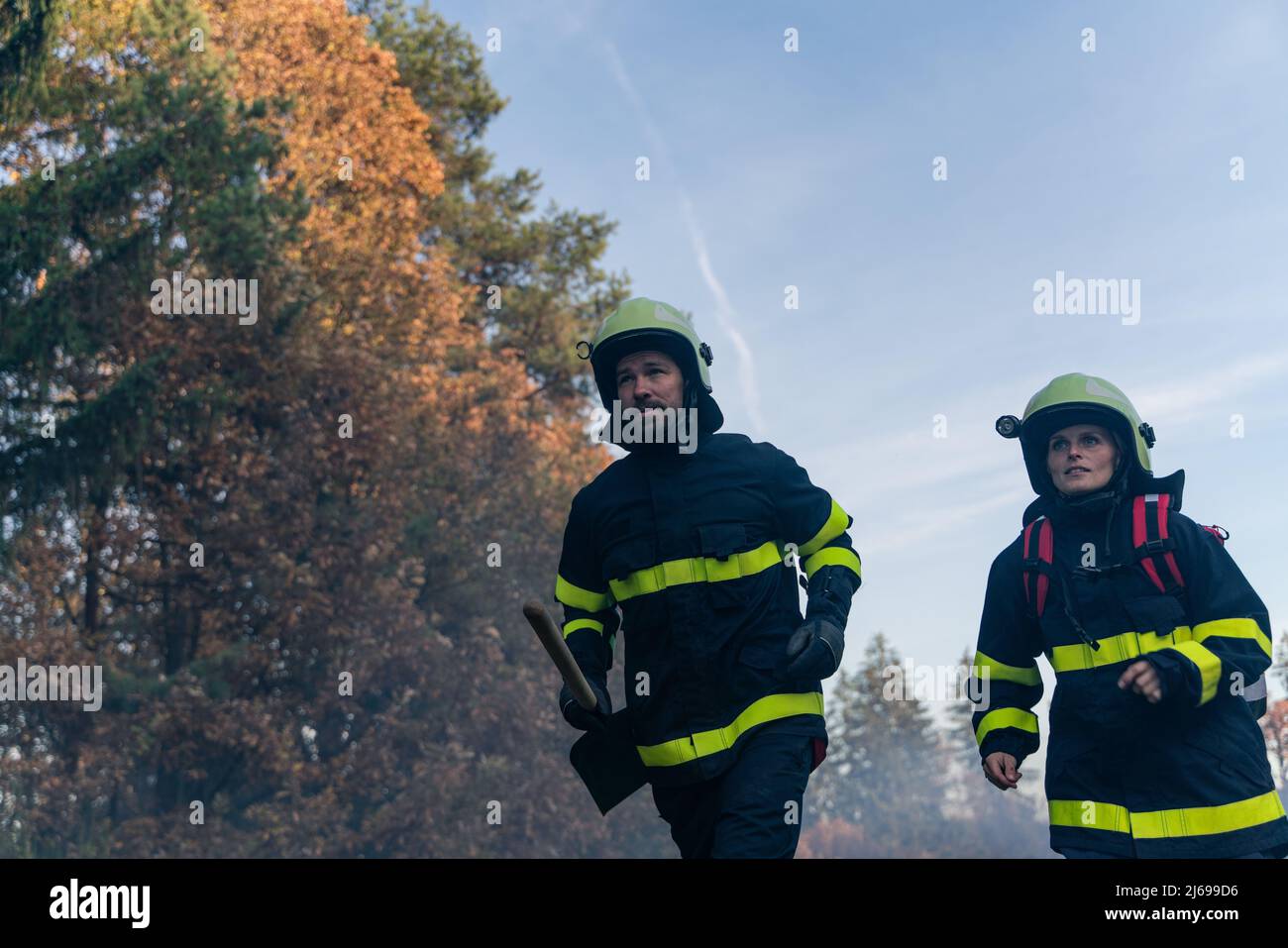 Firefighters man and woman at action, running through smoke with ...
