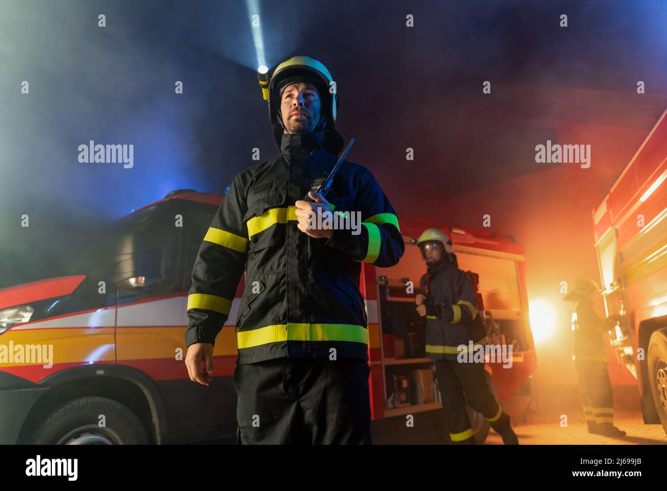Low angle view of firefighter with fire truck in background at night ...