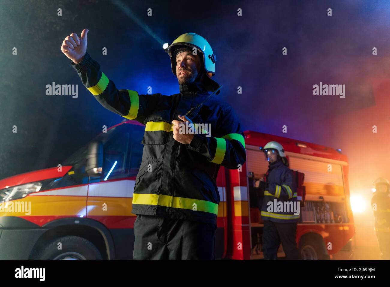 Low angle view of firefighter with fire truck in background at night ...