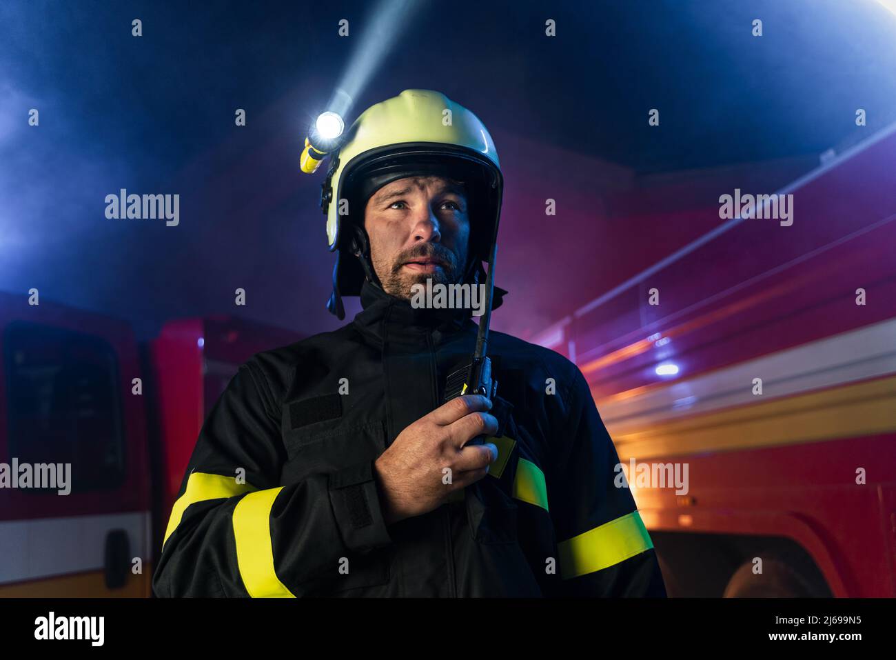 Low angle view of firefighter with fire truck in background at night ...