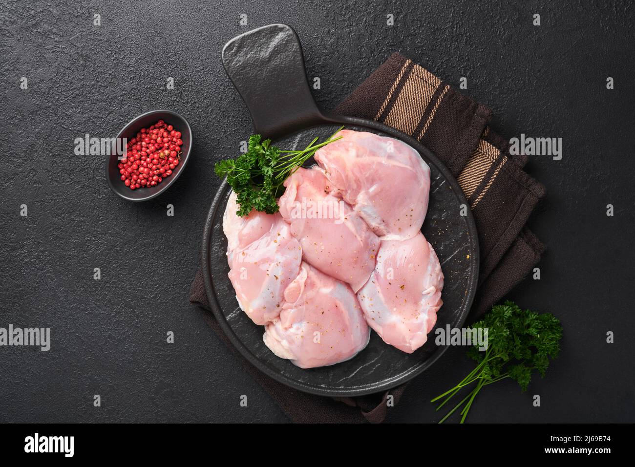 Raw chicken thigh fillet without skin with herbs and spices on black ...