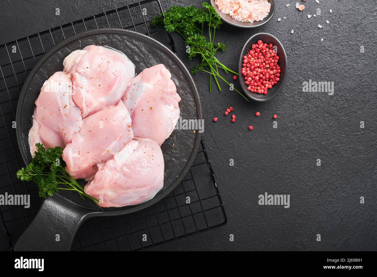 Raw chicken thigh fillet without skin with herbs and spices on black ...