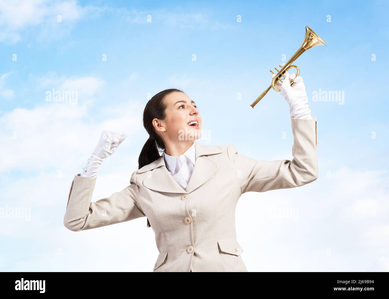 Beautiful woman holding trumpet brass overhead Stock Photo - Alamy