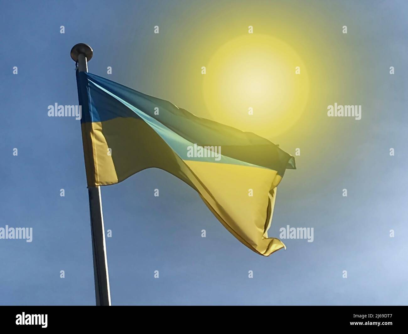 Ukrainian flag waving in the wind against a blue sky and a big yellow ...