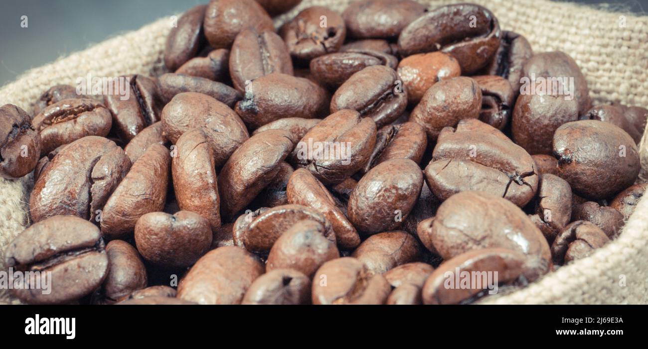 Dark roasted fragrant coffee beans in jute bag on concrete structure ...