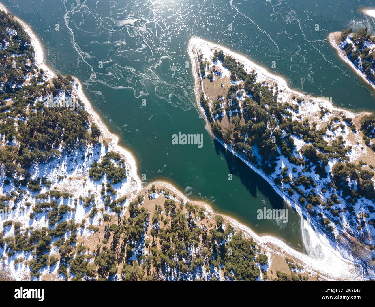 Aerial winter view of Dospat Reservoir covered with ice, Smolyan Region ...