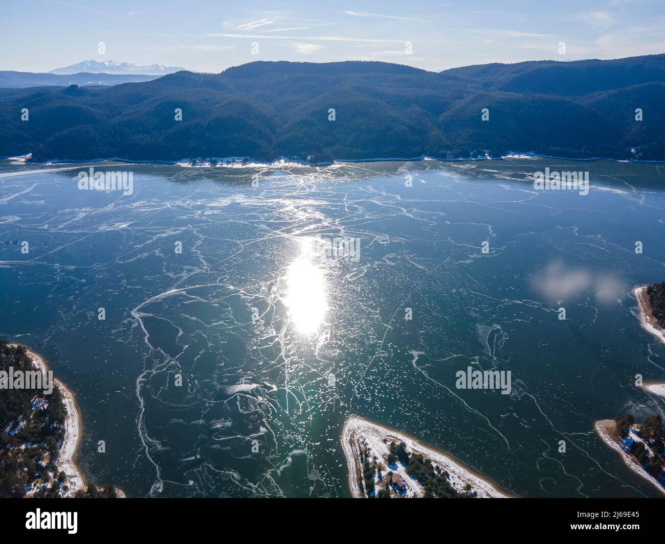 Aerial winter view of Dospat Reservoir covered with ice, Smolyan Region ...