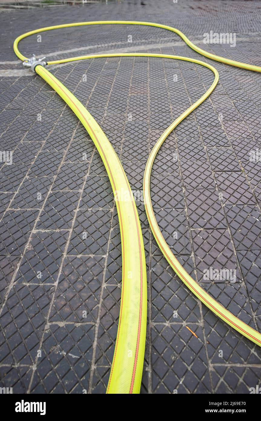 Yellow fire hose lies on a cobbled road, outdoors. Fire truck equipment ...