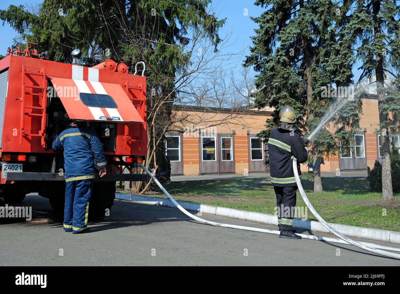 Fireman set hoses out, another one checking a water pump during ...