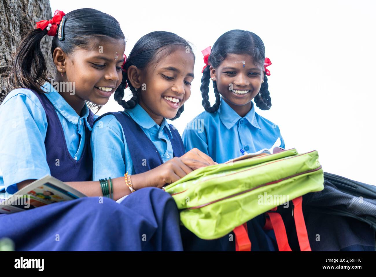 teenager school girl kids busy reading book while sitting under tree ...