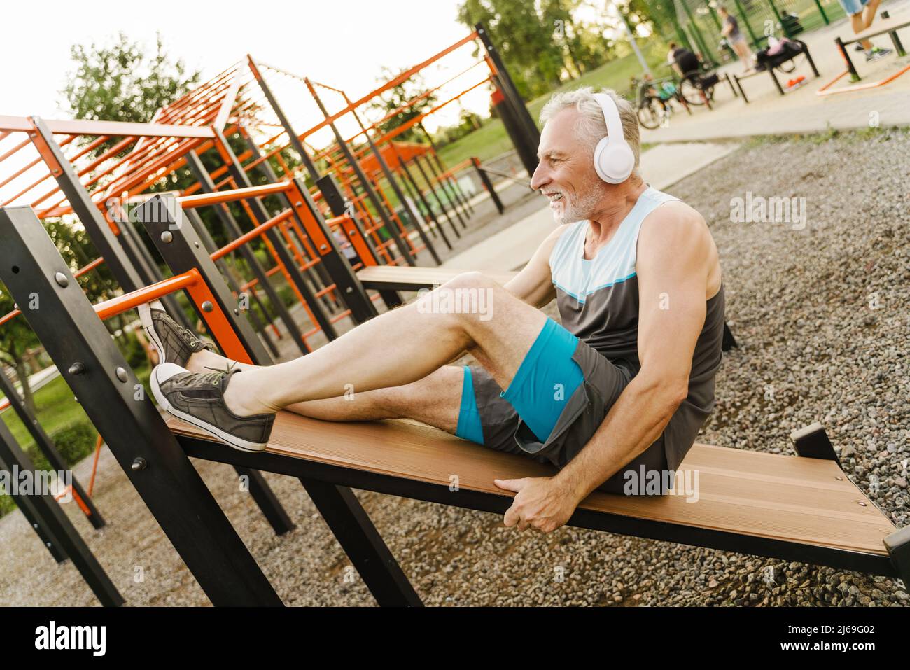 Grey senior man listening music while working out on equipment on ...