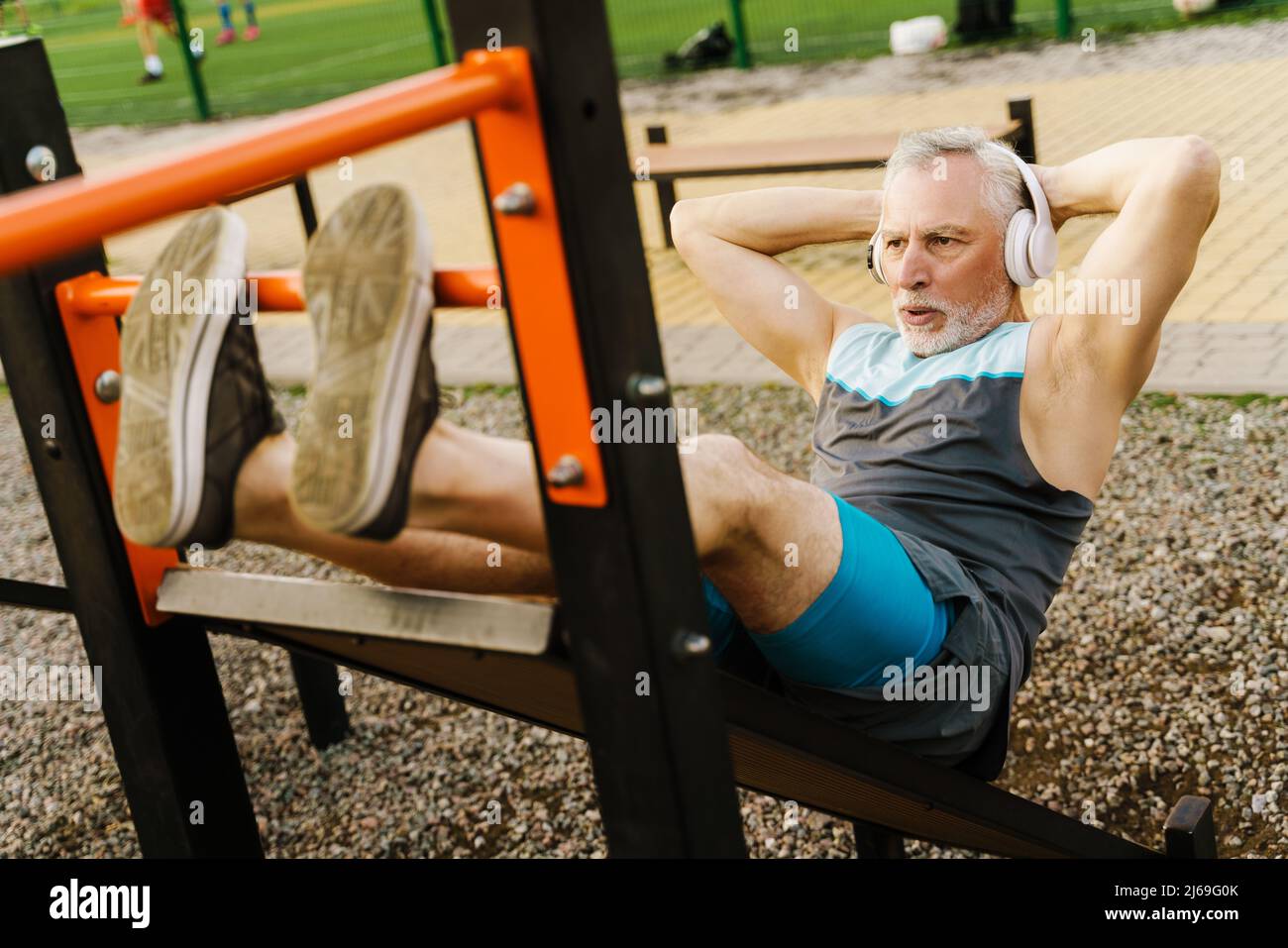 Grey senior man listening music while working out on equipment on ...