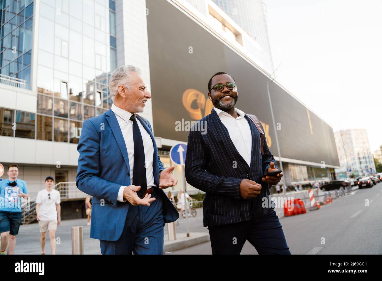 Multiracial men talking and using cellphone while walking on city ...