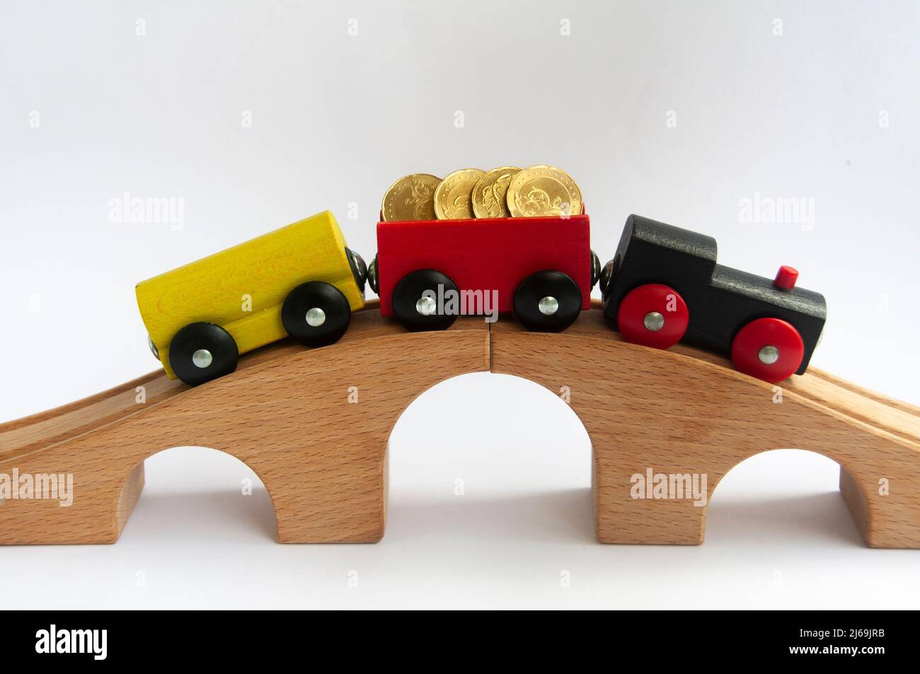 Wooden toy train with gold coins. Conceptual Stock Photo - Alamy