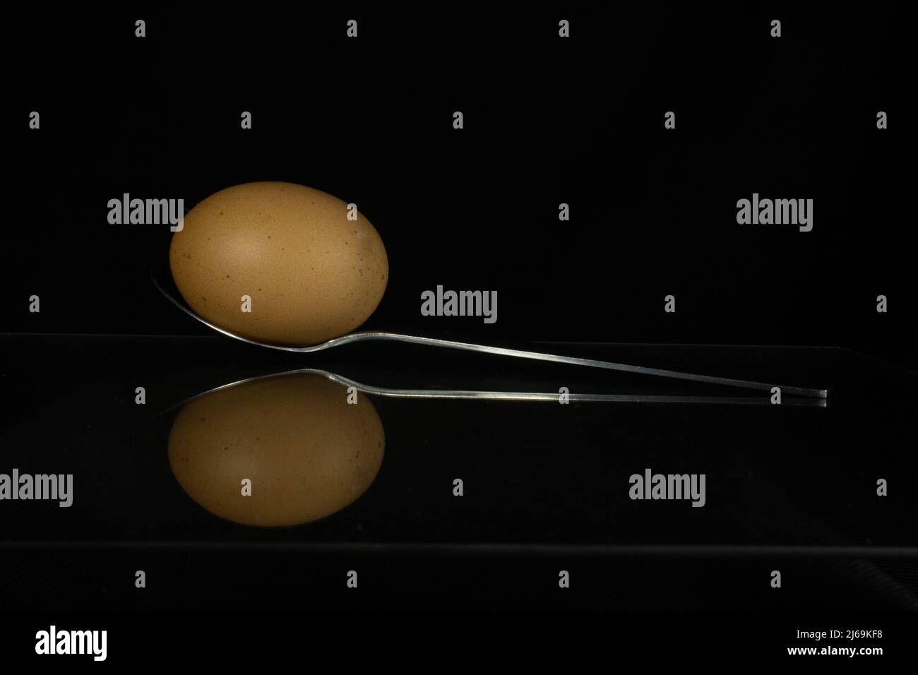 a single silver table spoon with a balanced egg reflected and isolated ...