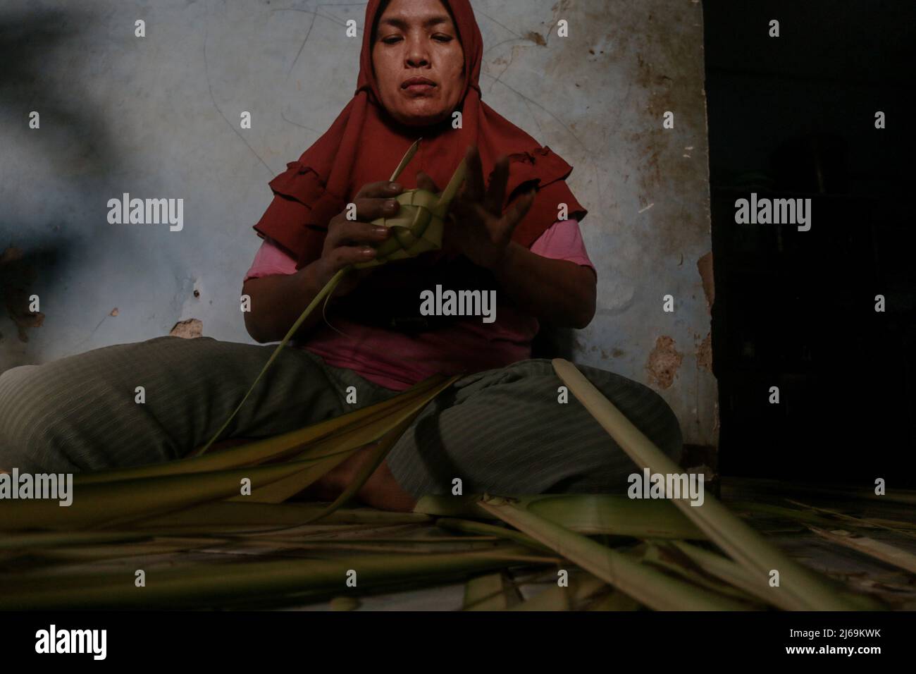 Indonesian vendors weave palm leaves used to make traditional rice ...