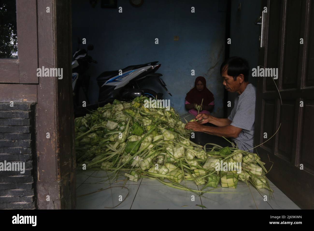 Indonesian vendors weave palm leaves used to make traditional rice ...