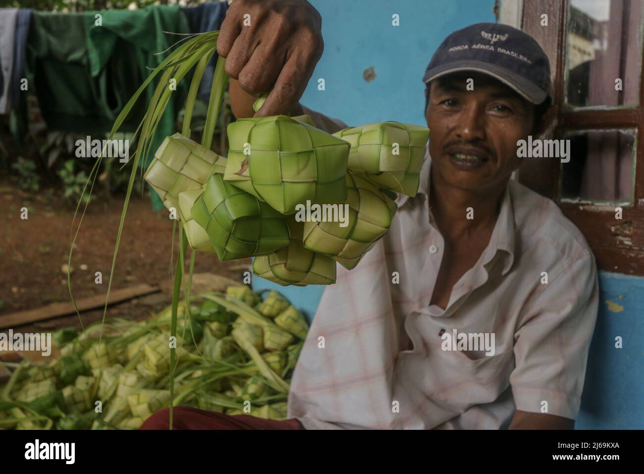 Indonesian vendors weave palm leaves used to make traditional rice ...
