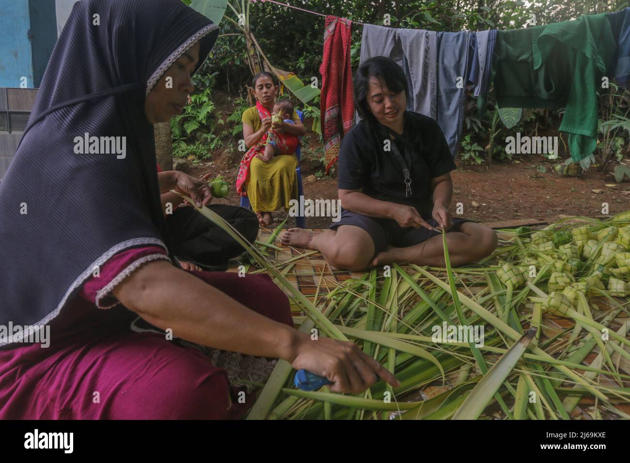 Indonesian vendors weave palm leaves used to make traditional rice ...