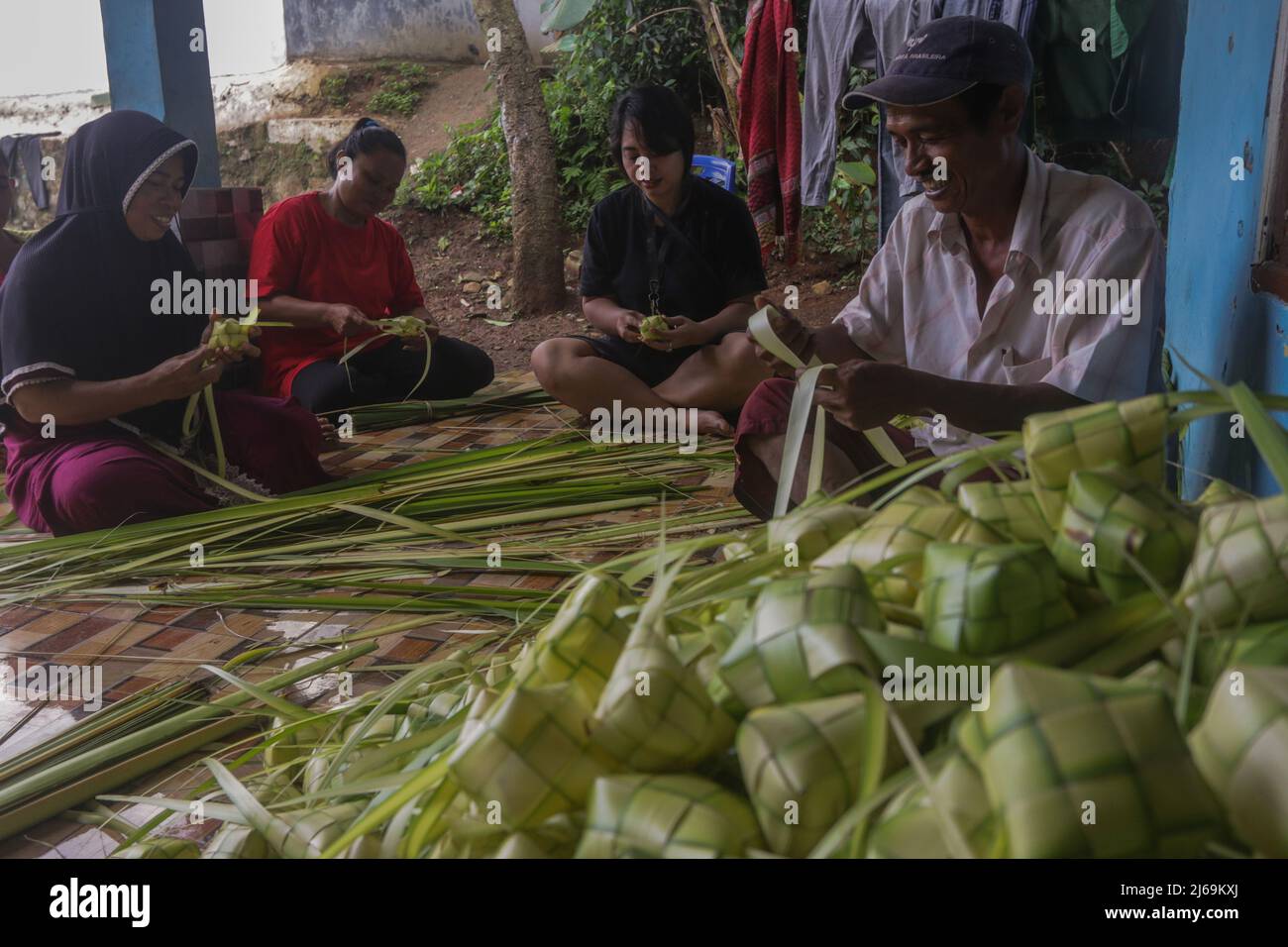 Indonesian vendors weave palm leaves used to make traditional rice ...
