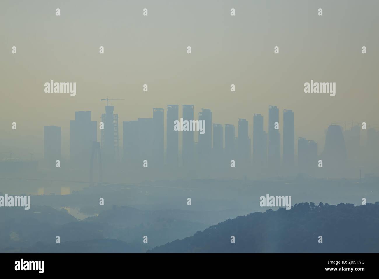 Distant view of tall buildings silhouettes in the distance under dense ...